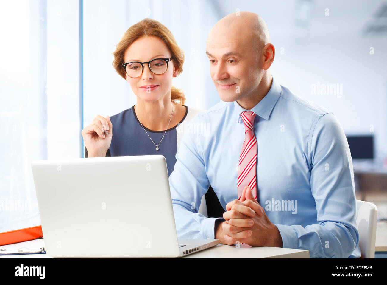 Mature business woman and senior businessman working together on laptop ...