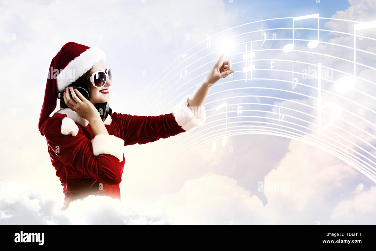 Young attractive Santa girl listening music in headphones Stock Photo ...