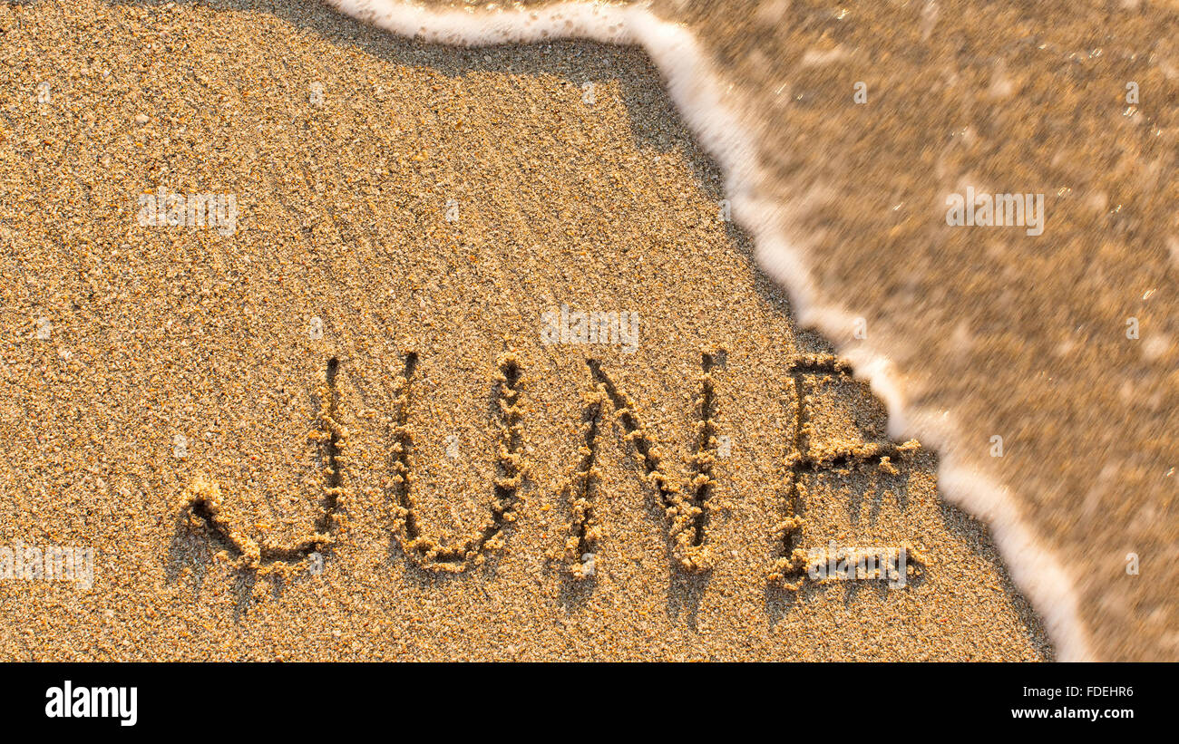 Inscription JUNE on a gentle beach sand with the soft wave (months of ...