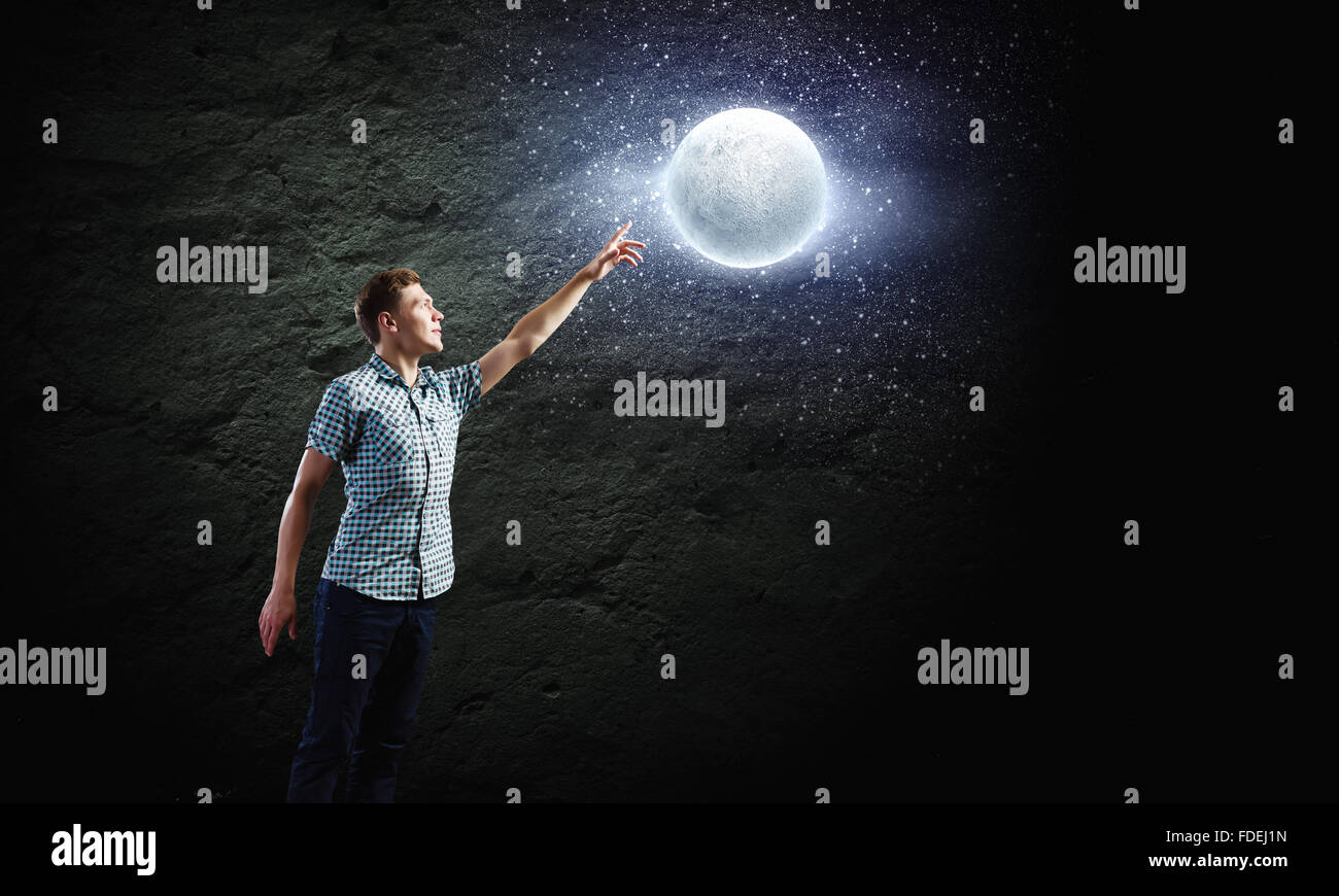 Young man and moon planet against dark background Stock Photo - Alamy