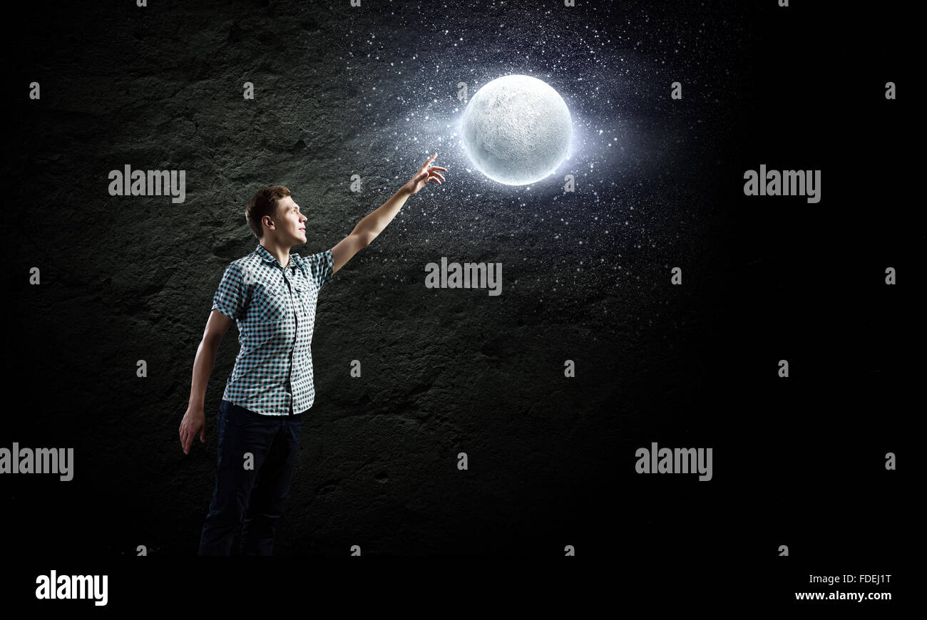 Young man and moon planet against dark background Stock Photo - Alamy