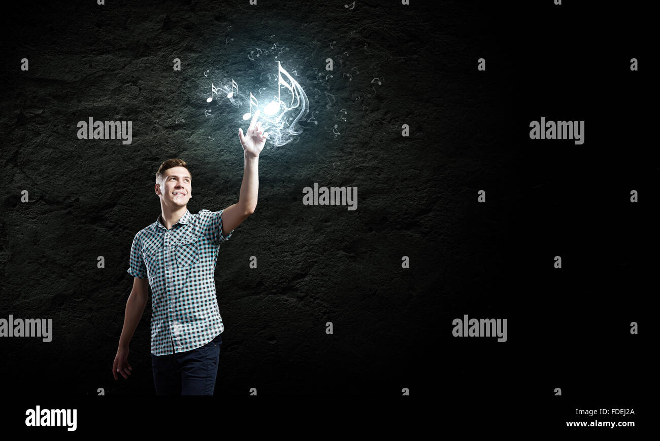Young handsome man touching music clef icon Stock Photo - Alamy