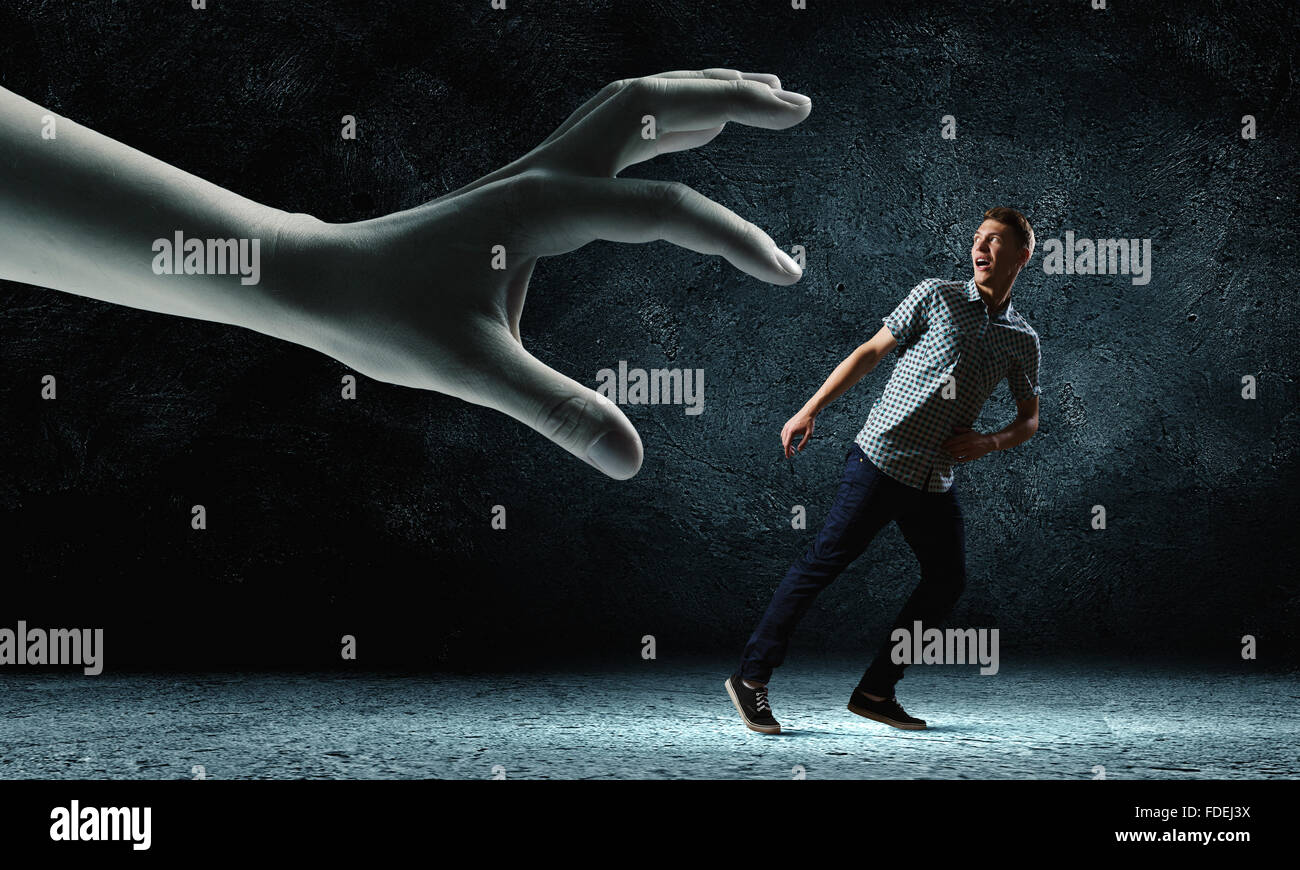 Funny image of young man trying to escape from huge hand Stock Photo ...