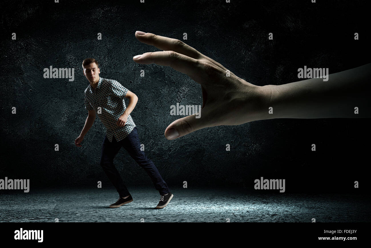 Funny image of young man trying to escape from huge hand Stock Photo ...