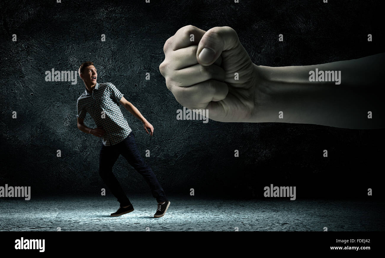 Funny image of young man trying to escape from huge hand Stock Photo ...