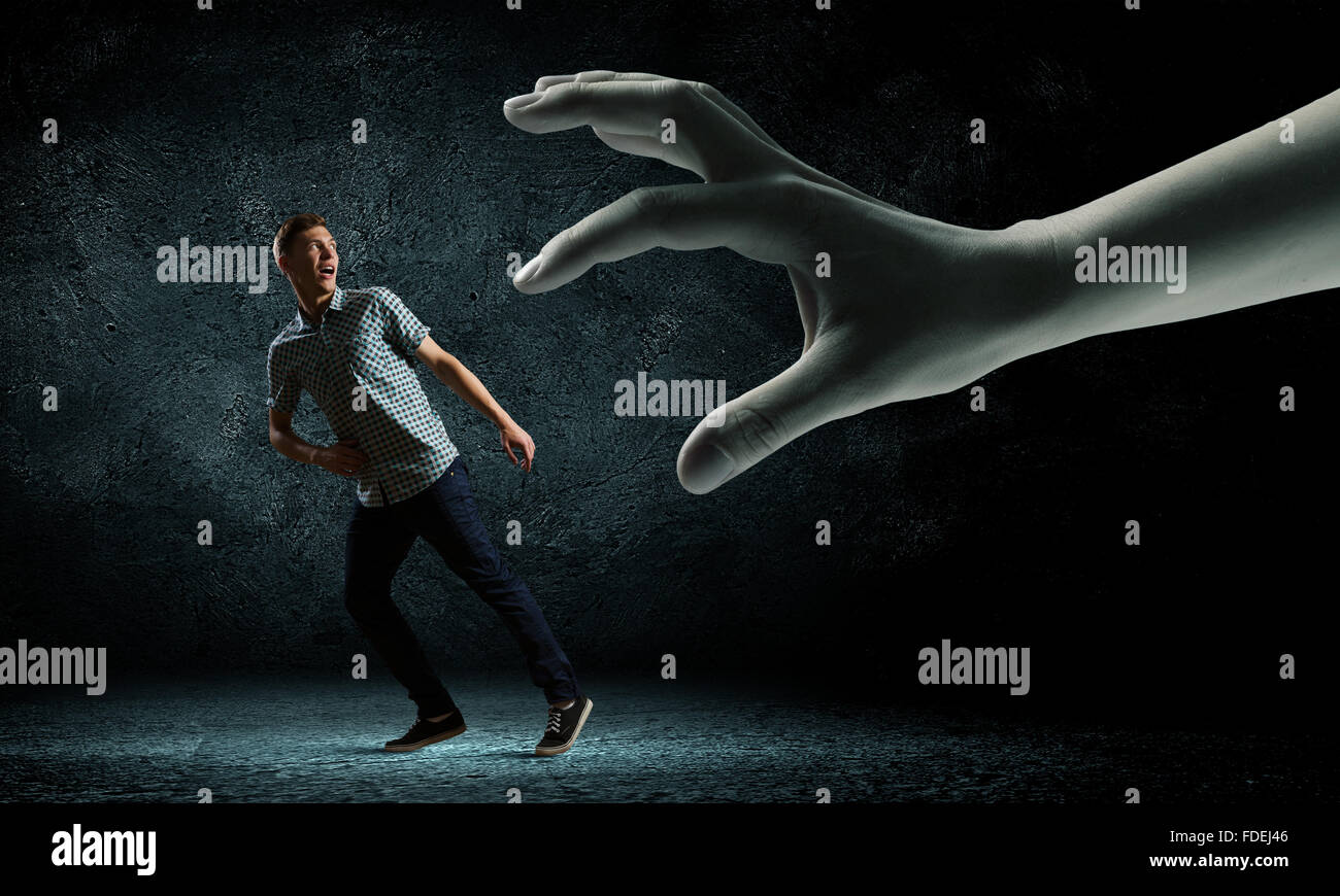 Funny image of young man trying to escape from huge hand Stock Photo ...