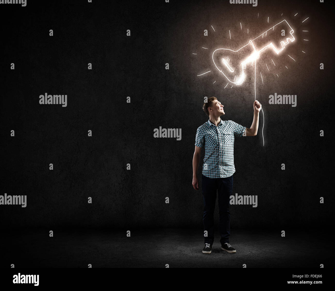Young man catching key against dark background Stock Photo - Alamy