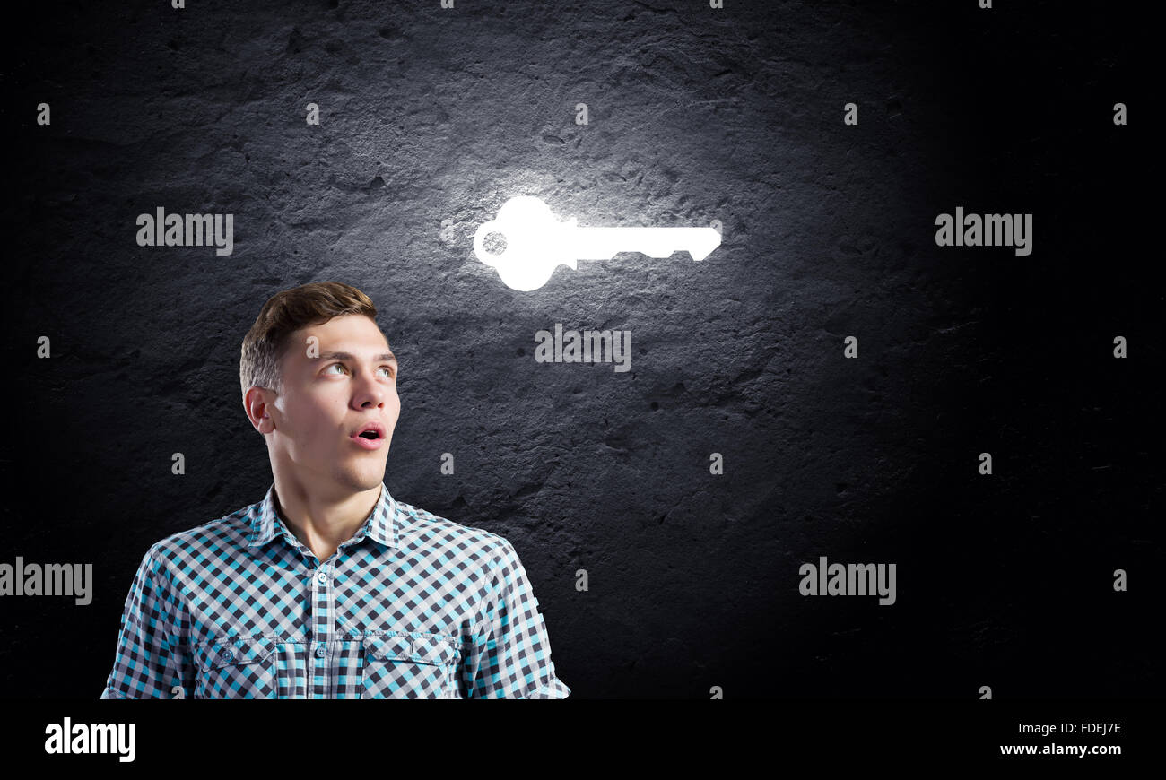 Young man with key against dark background Stock Photo - Alamy