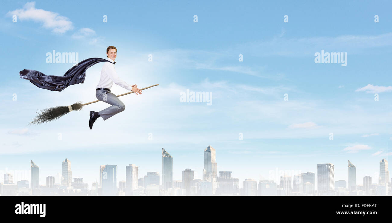 Young businessman flying on broom high in sky Stock Photo - Alamy
