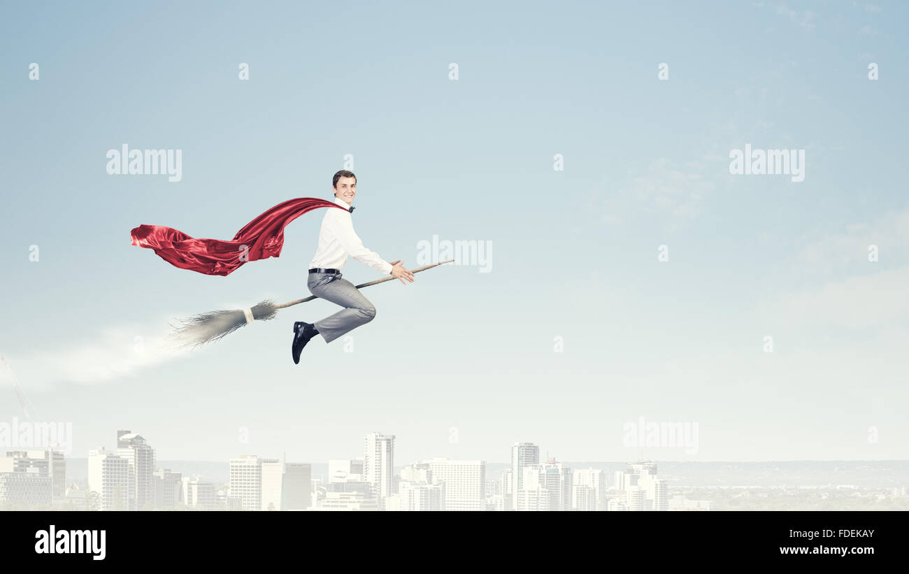 Young businessman flying on broom high in sky Stock Photo - Alamy