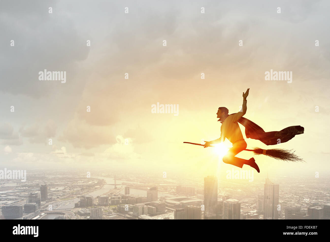 Young businessman flying on broom high in sky Stock Photo - Alamy