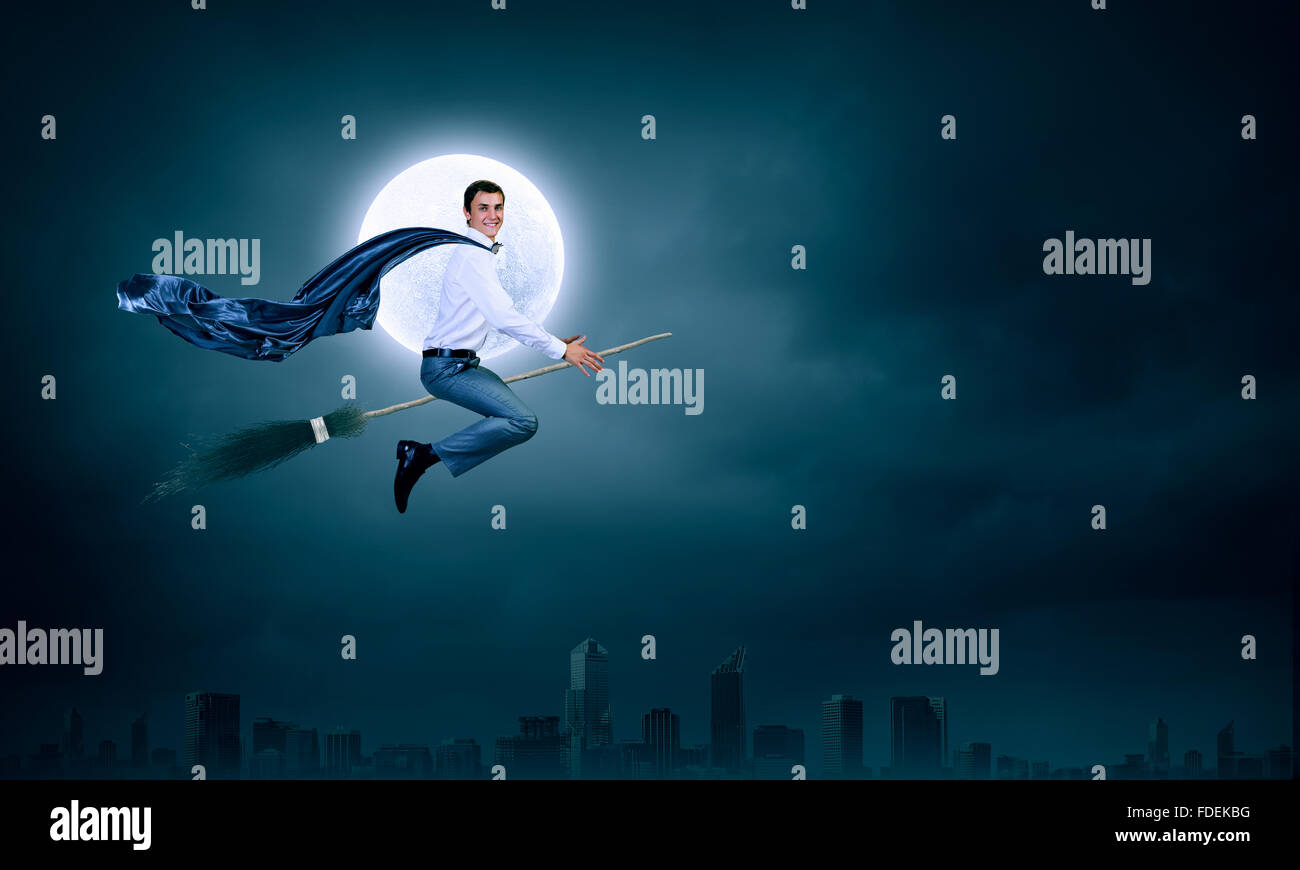 Young businessman flying on broom high in sky Stock Photo - Alamy