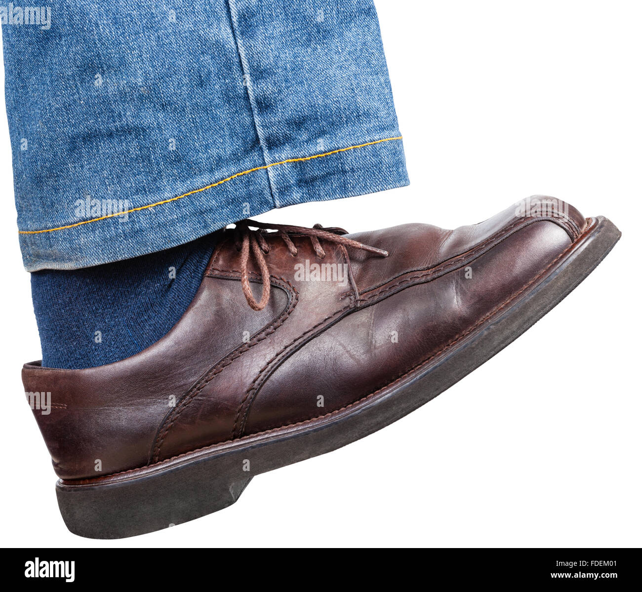 side view of male right foot in jeans and brown shoe takes a step ...