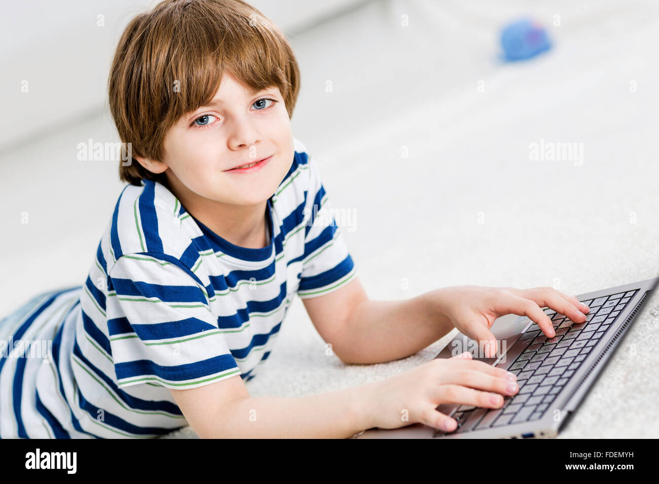 Cute boy lying on floor and using laptop Stock Photo - Alamy