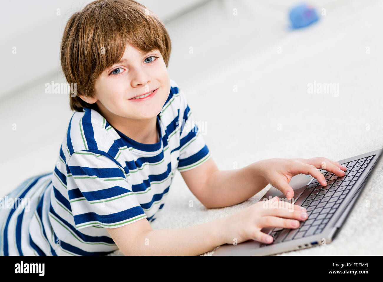 Cute boy lying on floor and using laptop Stock Photo - Alamy