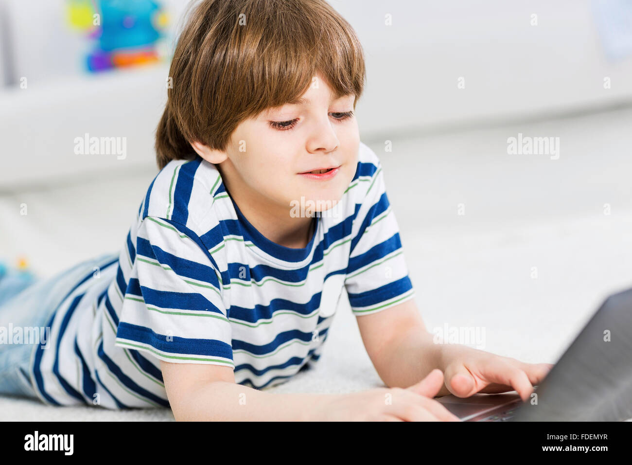 Cute boy lying on floor and using laptop Stock Photo - Alamy