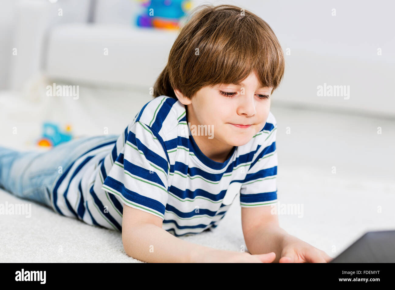 Cute boy lying on floor and using laptop Stock Photo - Alamy
