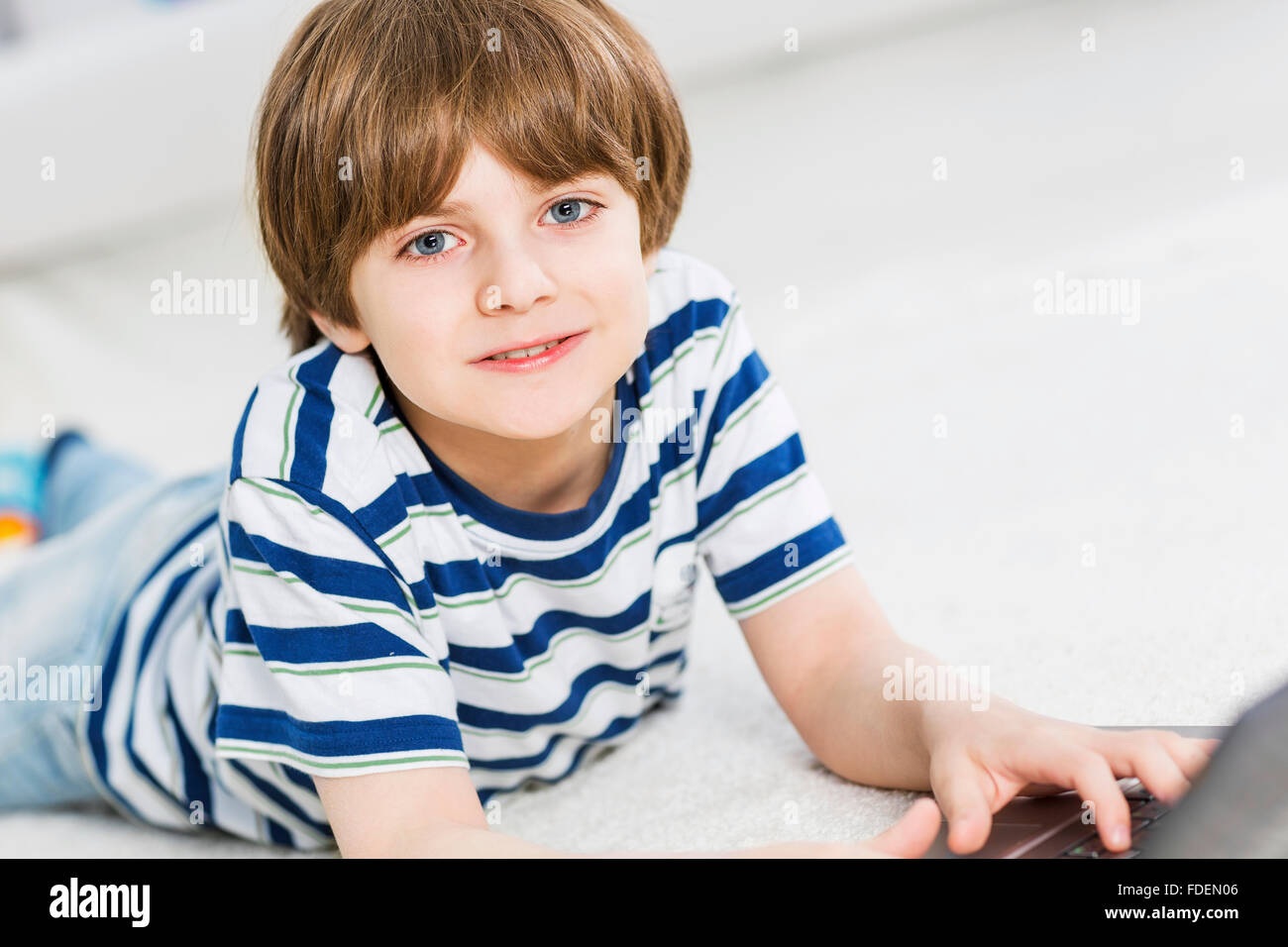 Cute boy lying on floor and using laptop Stock Photo - Alamy