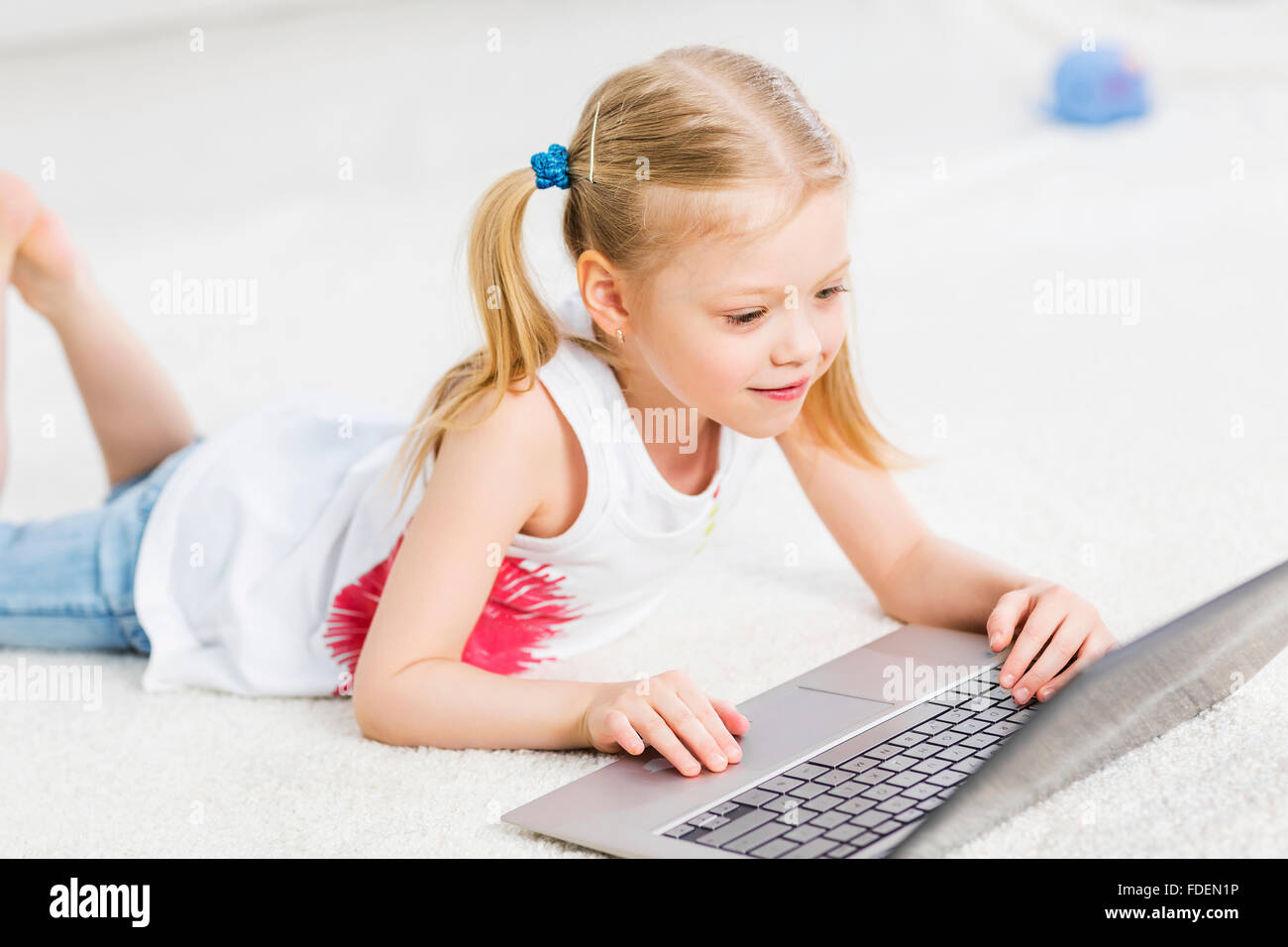 Cute girl laying on the floor and play at laptop Stock Photo - Alamy