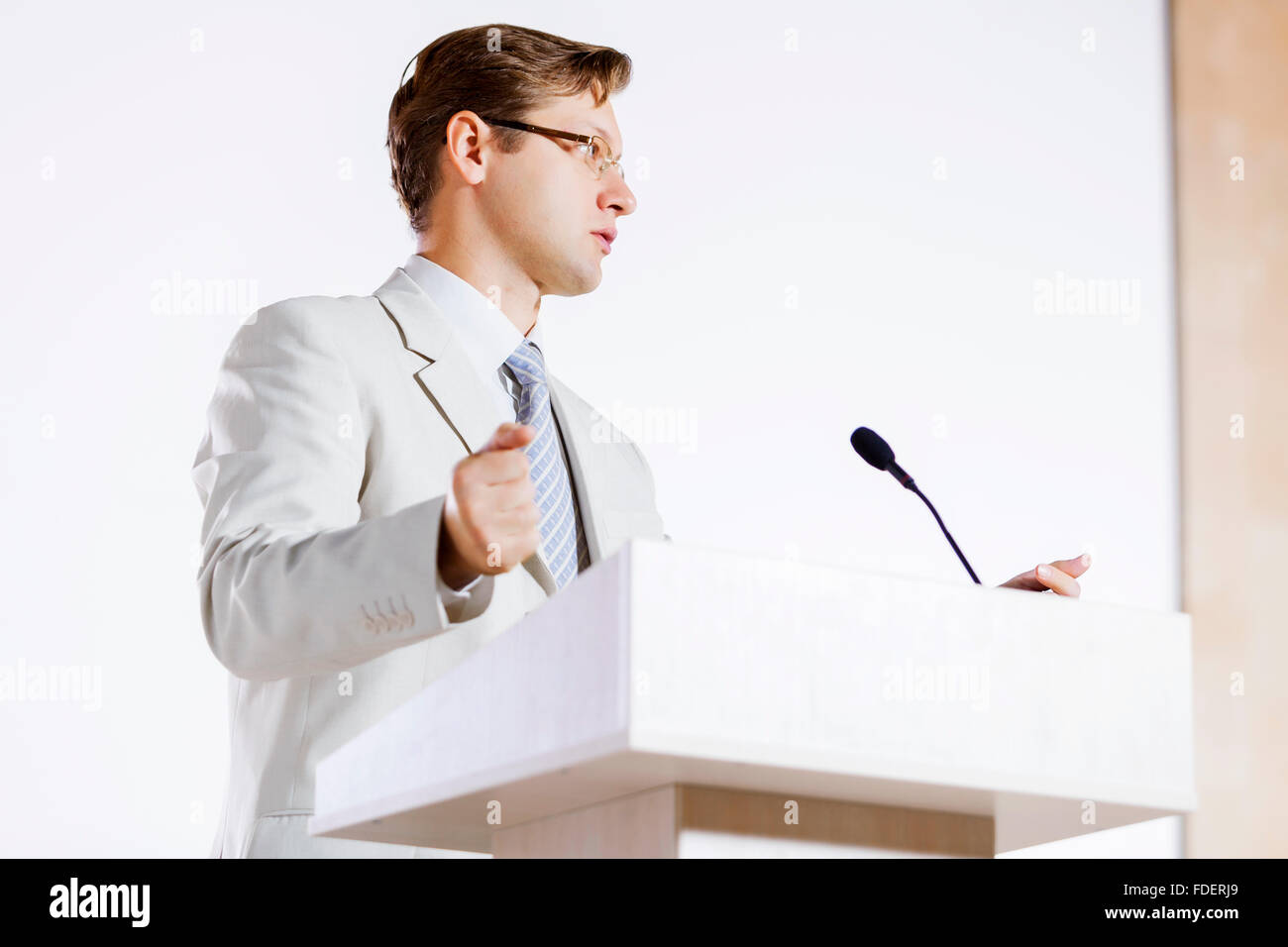 Young businessman standing on stage and speaking to microphone Stock ...