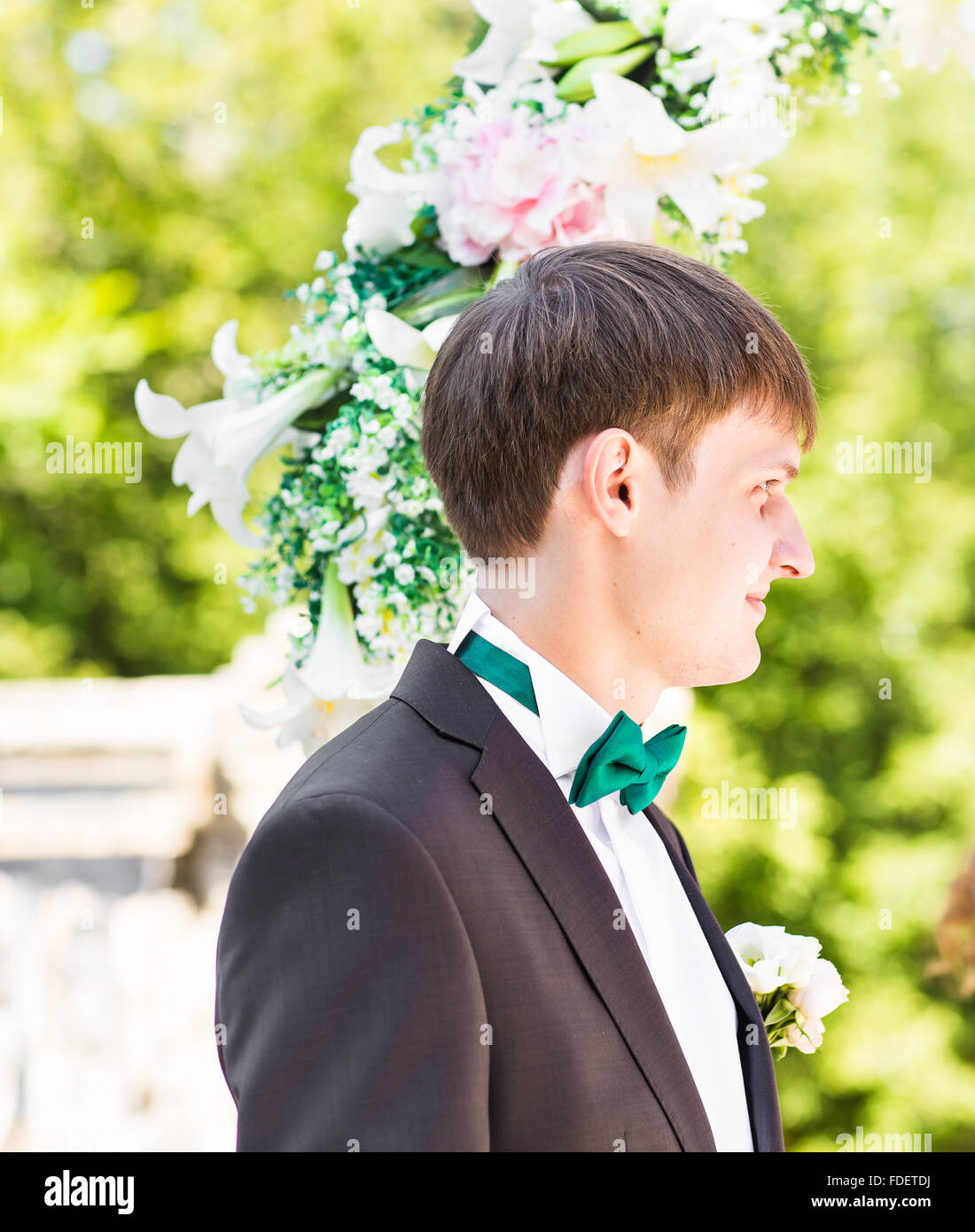 Elegant stylish groom having wedding ceremony on the background of arch ...