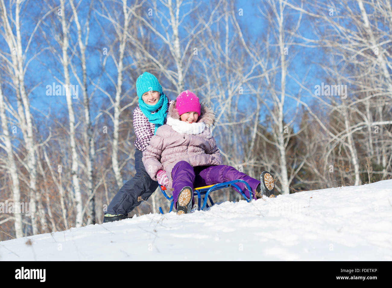 Two cute girls enjoying sledge ride in beautiful snowy winter park ...