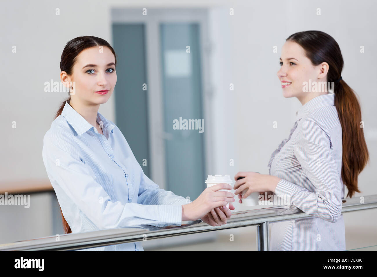 Two women standing at balcony with plastic cups and talking Stock Photo ...