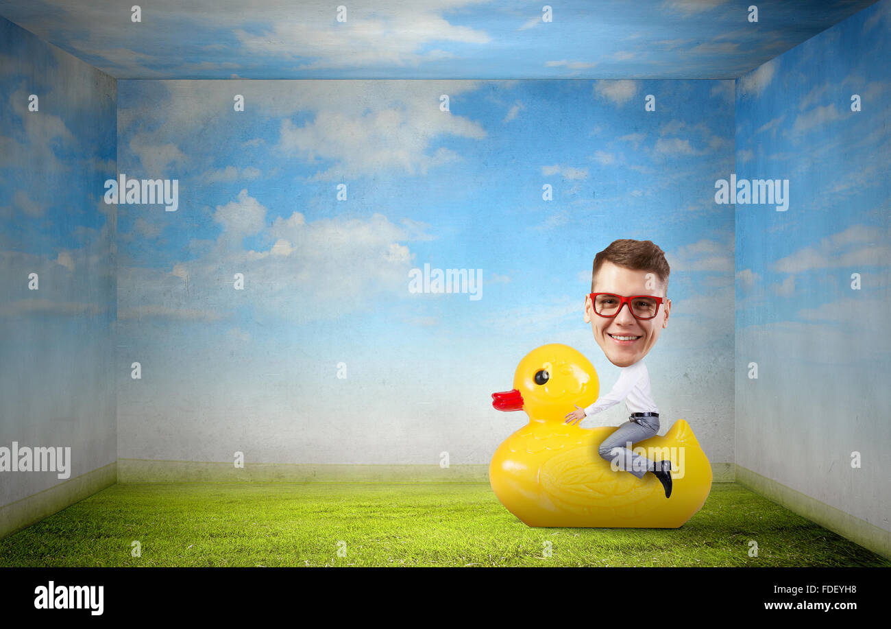 Young happy businessman riding yellow rubber duck Stock Photo - Alamy