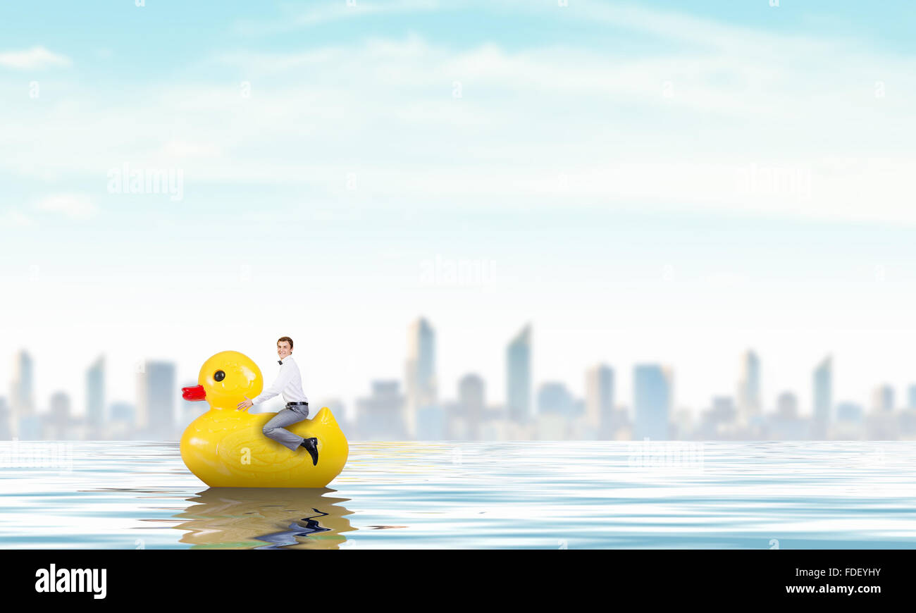 Young happy businessman riding yellow rubber duck Stock Photo - Alamy