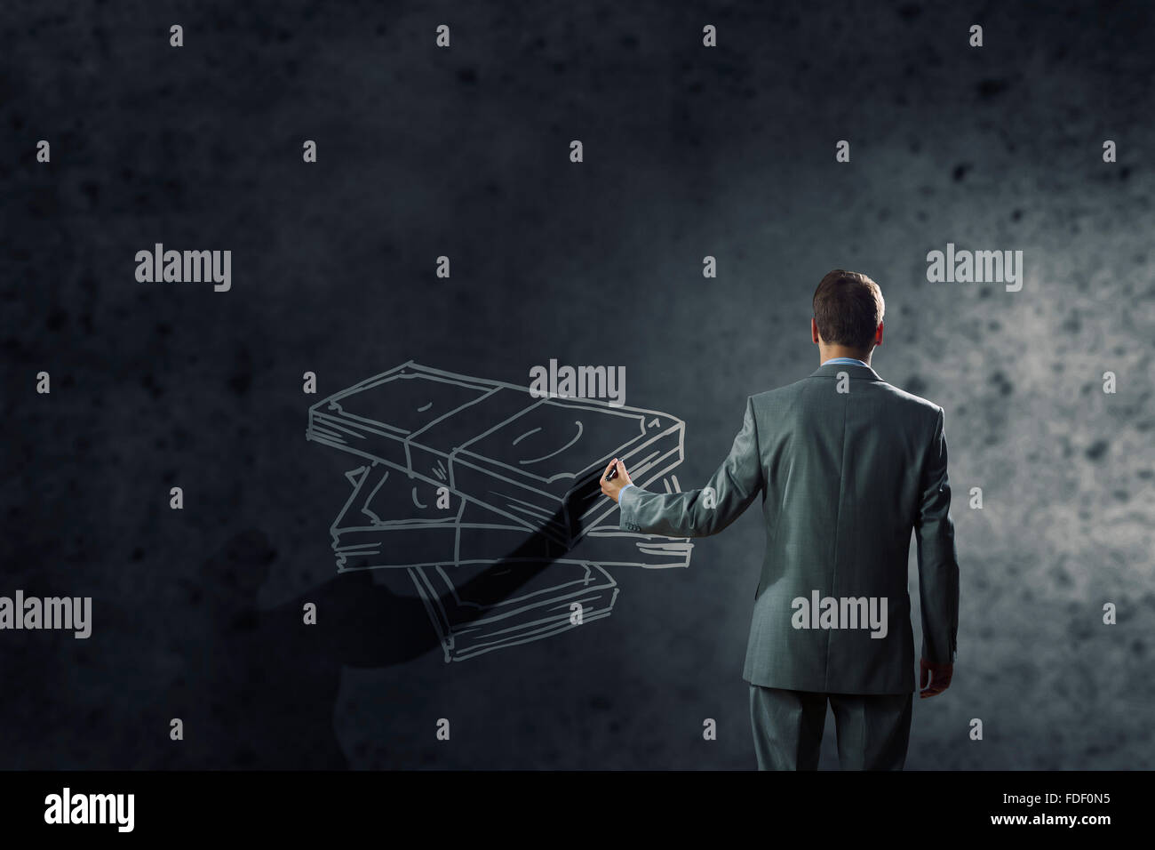 Back view of businessman drawing money banknotes on wall Stock Photo ...