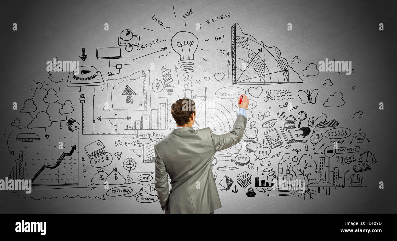 Rear view of businessman drawing business sketch on wall Stock Photo ...