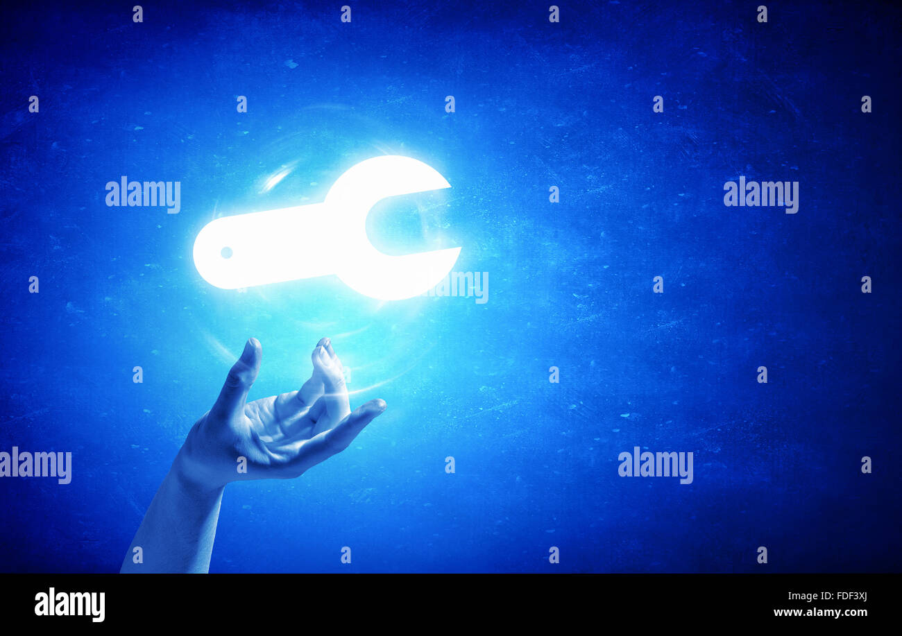 Person hand taking glowing tool sign on blue background Stock Photo - Alamy