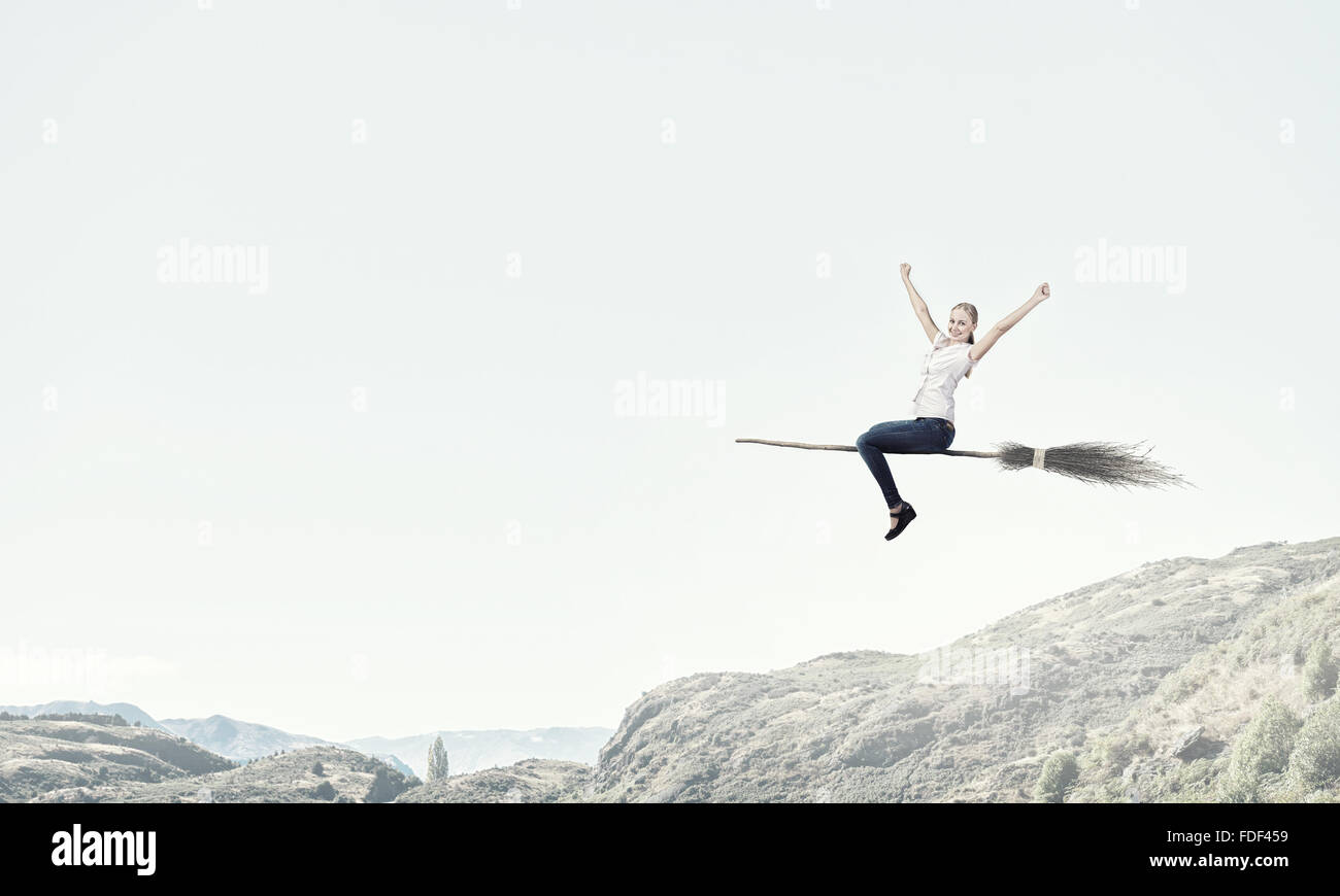 Happy young woman flying in sky on broom Stock Photo - Alamy