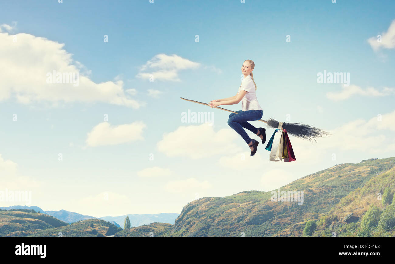 Happy young woman flying in sky on broom Stock Photo - Alamy
