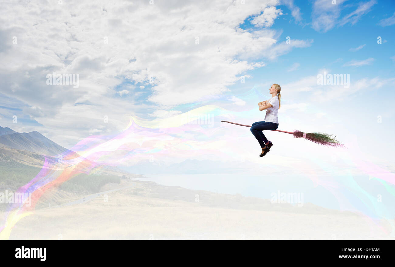 Happy young woman flying in sky on broom Stock Photo - Alamy