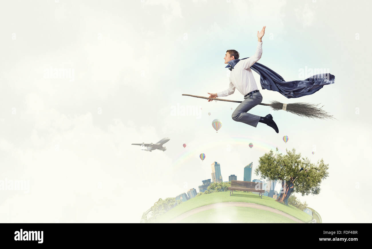 Young businessman flying on broom high in sky Stock Photo - Alamy