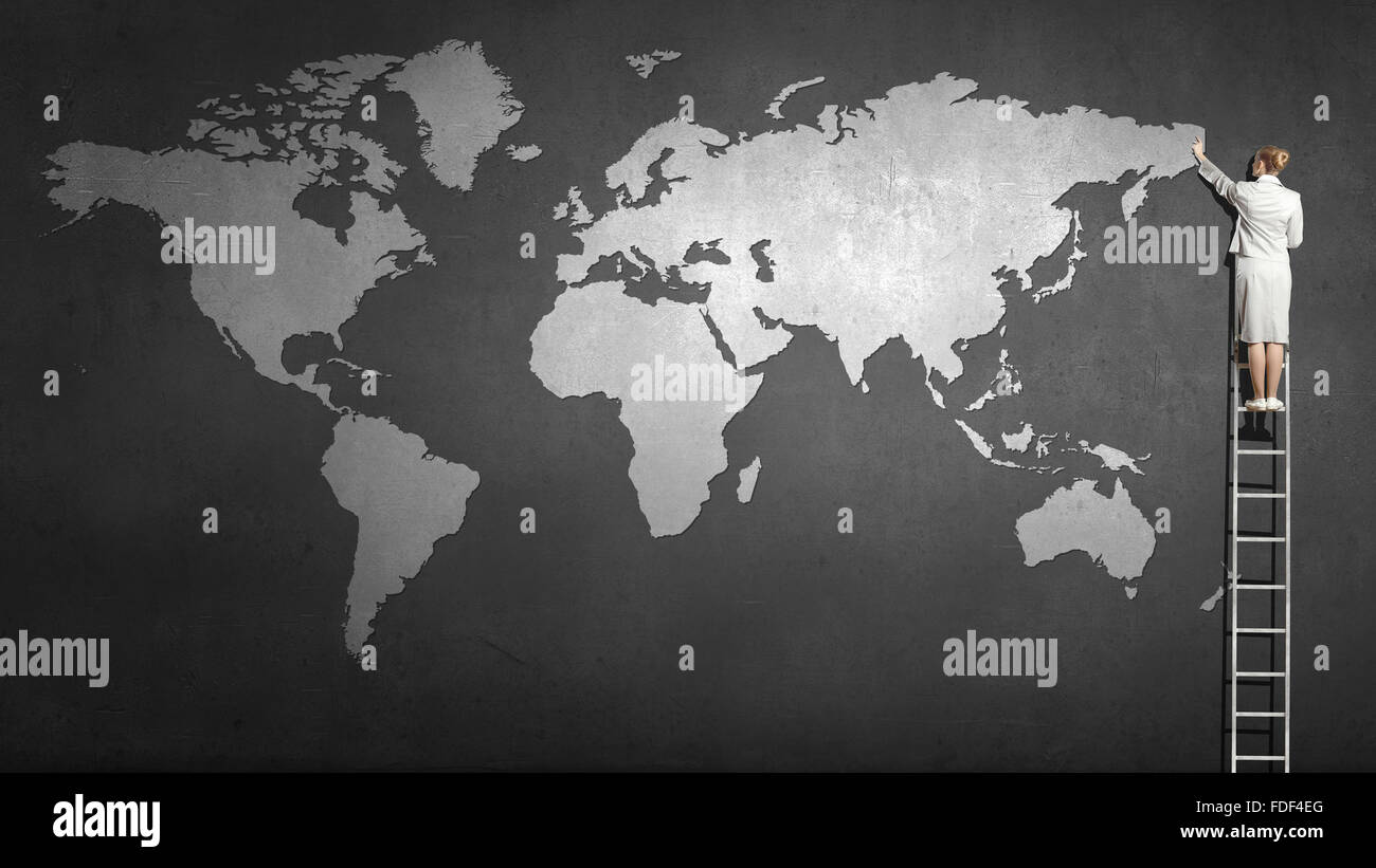 Back view of businesswoman standing on ladder and touching world map ...