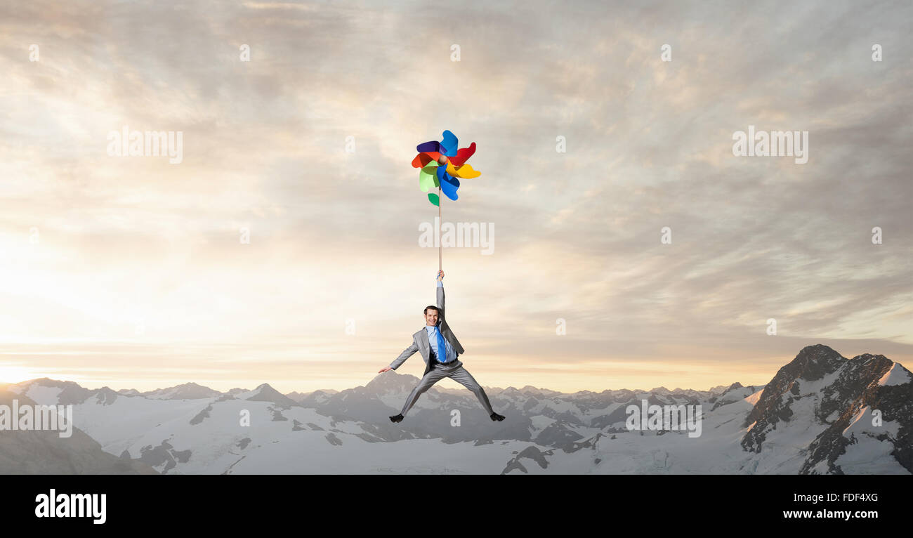Young happy businessman flying in sky on colorful windmill Stock Photo ...