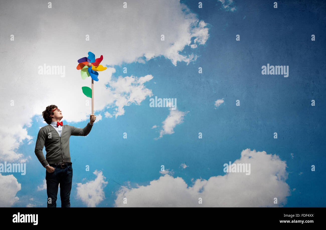 Young happy guy in casual with colorful windmill in hand Stock Photo ...