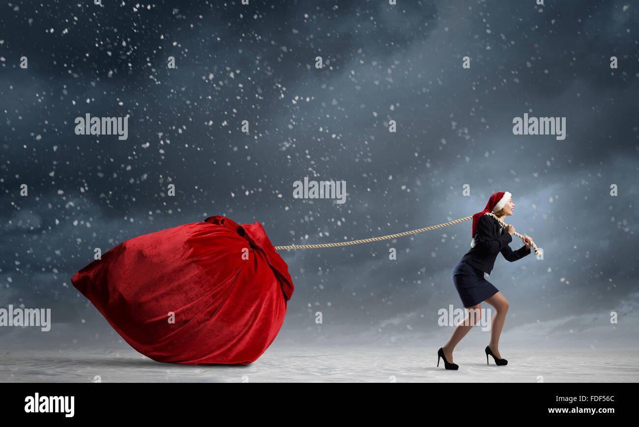 Santa woman pulling huge red gifts bag Stock Photo - Alamy