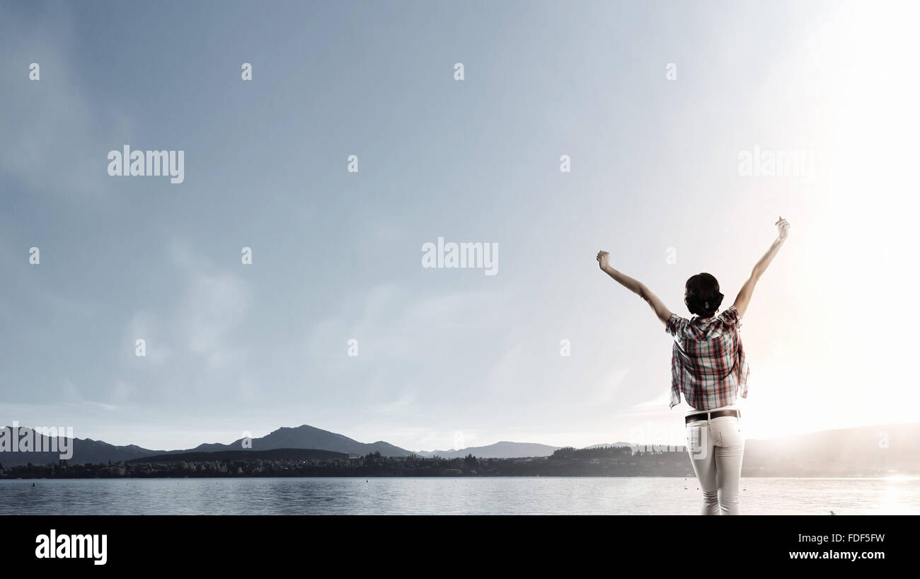 Back view of cheerful woman with hands up facing sunrise Stock Photo ...