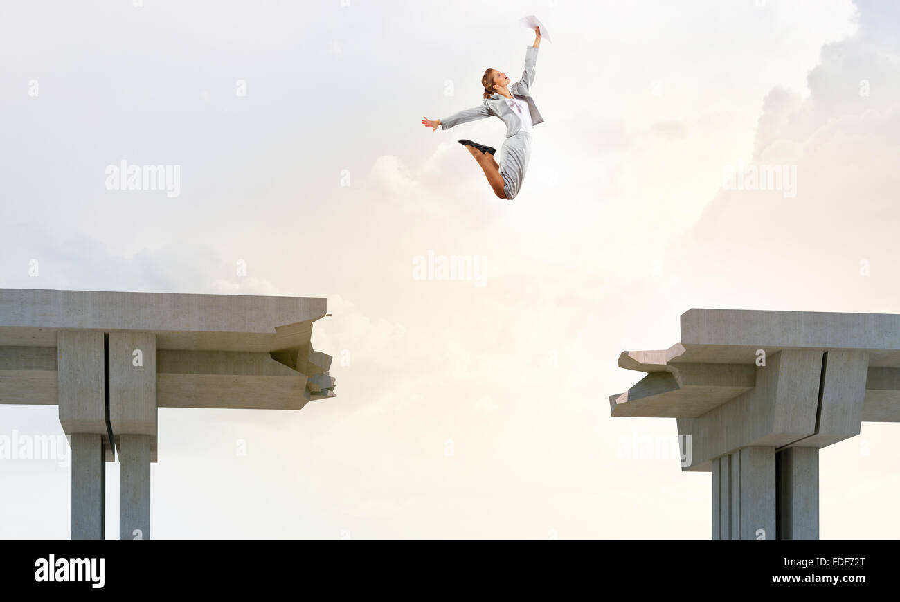 Young woman jumping over a gap in the bridge as a symbol of risk Stock ...