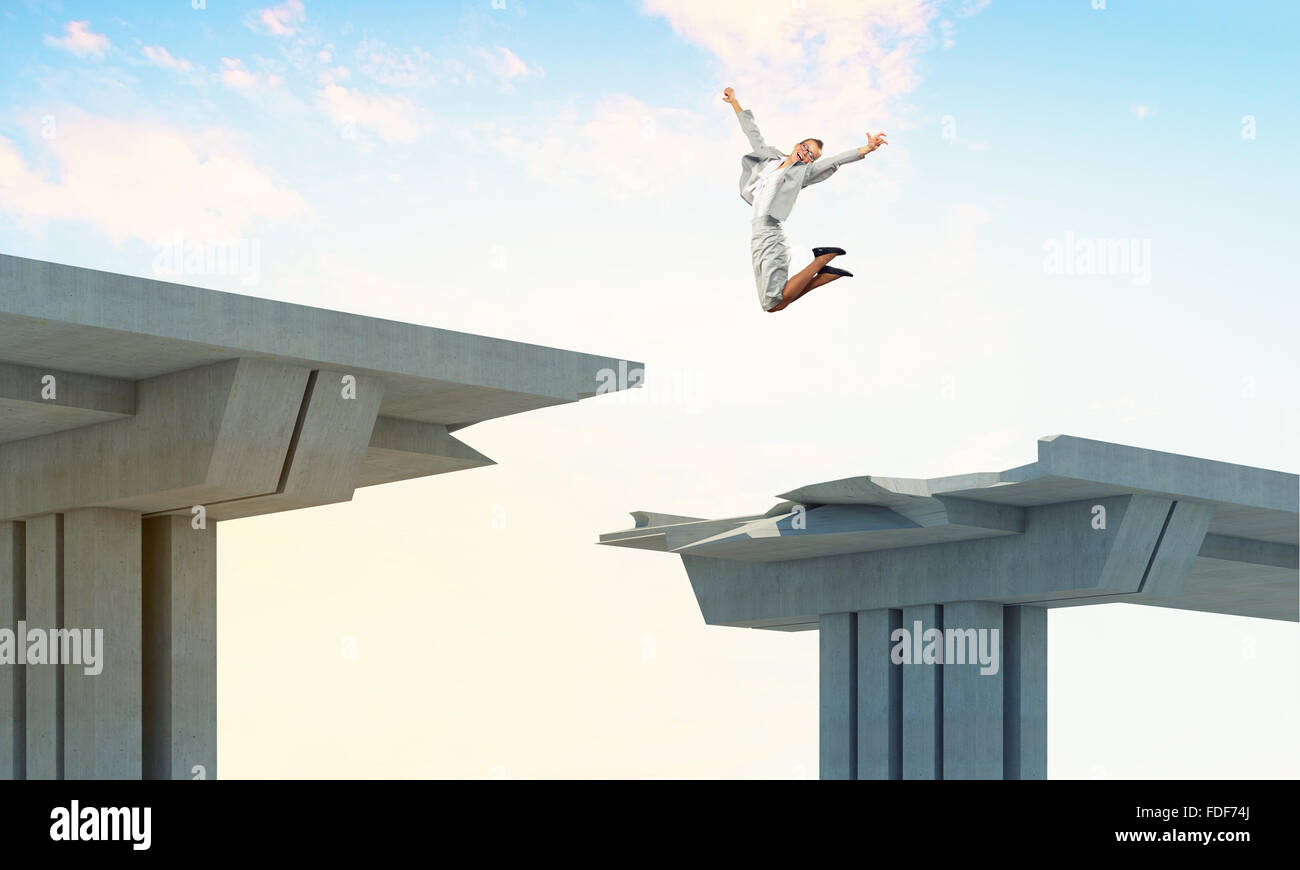 Young woman jumping over a gap in the bridge as a symbol of risk Stock ...