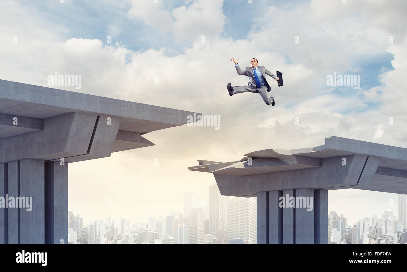 Businessman jumping over a gap in the bridge as a symbol of bridge ...