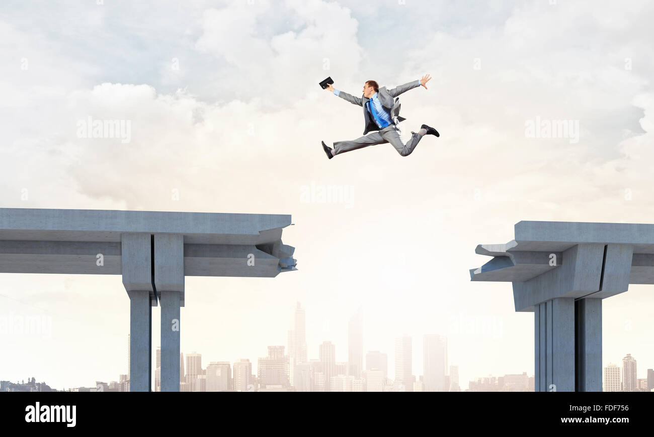 Businessman jumping over a gap in the bridge as a symbol of bridge ...