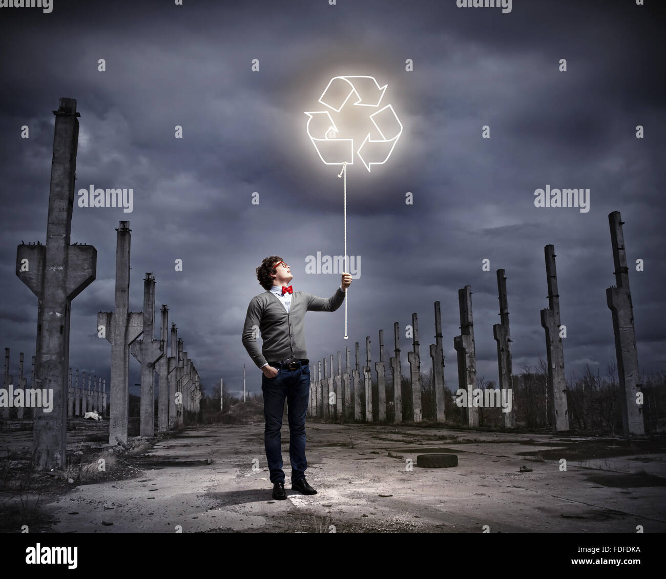 Young man with a recycle symbol against a polluted and ruined landscape ...