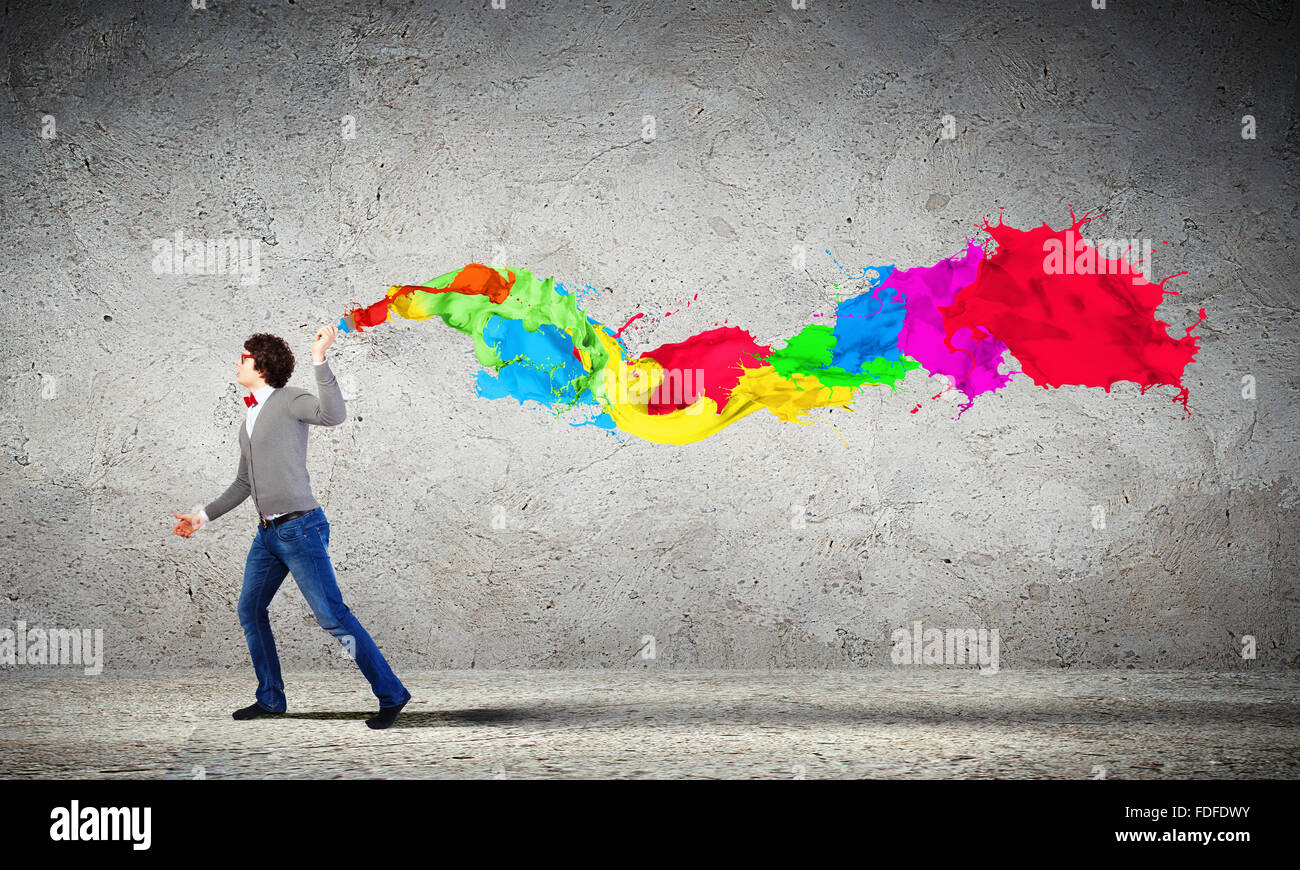 Young man spraying colour paints over background Stock Photo - Alamy