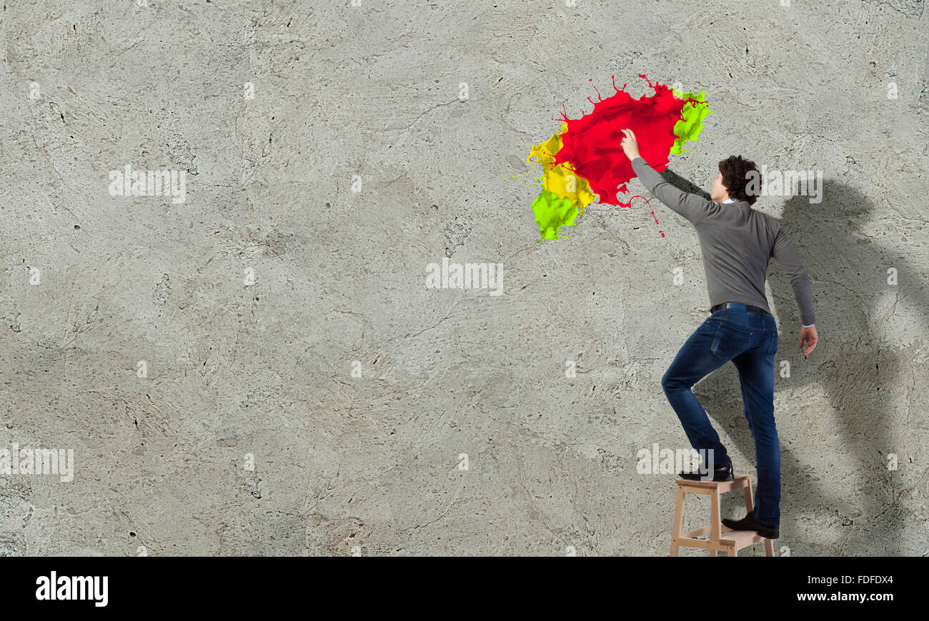 Young man spraying colour paints over background Stock Photo - Alamy
