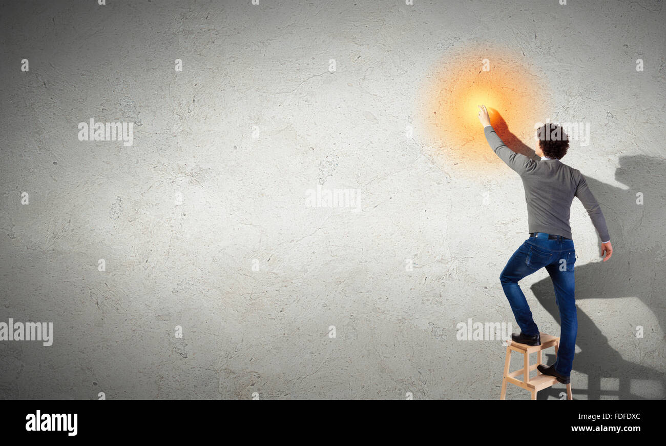 Young man with an electric light bulb against the wall Stock Photo - Alamy