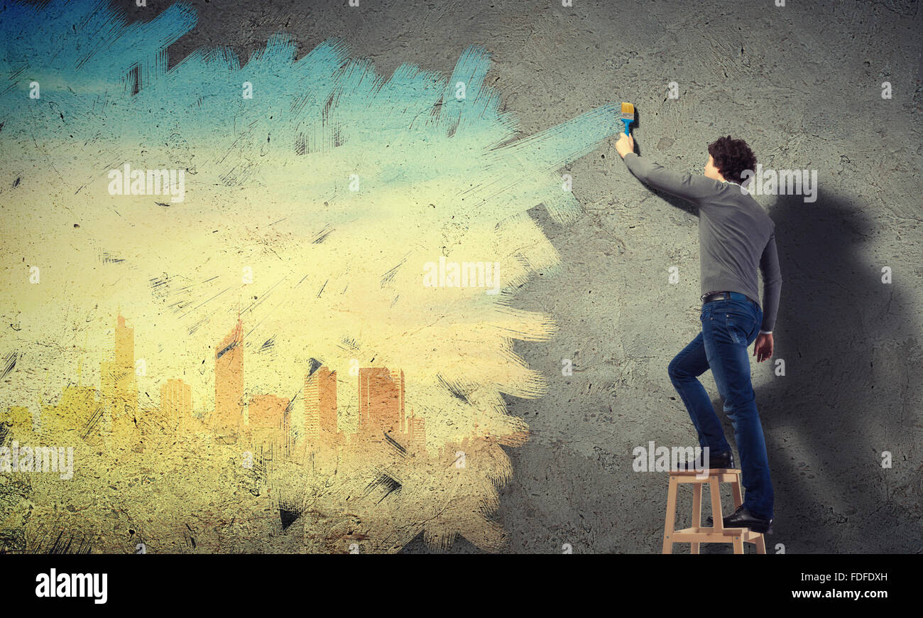 Young man painting a yellow colour cityscape on the wall Stock Photo ...